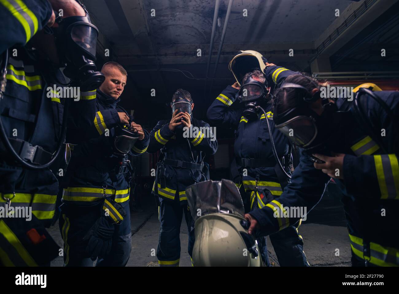 Group of firefighters standing inside the fire brigade wearing helmet ...