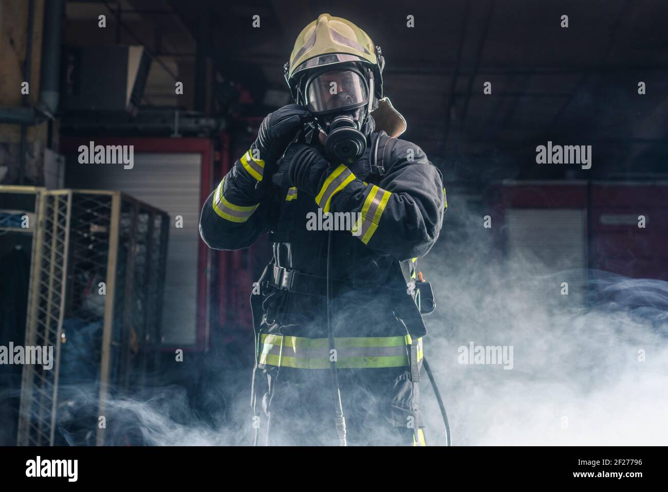 Portrait of a fireman wearing firefighter turnouts and helmet. Dark ...