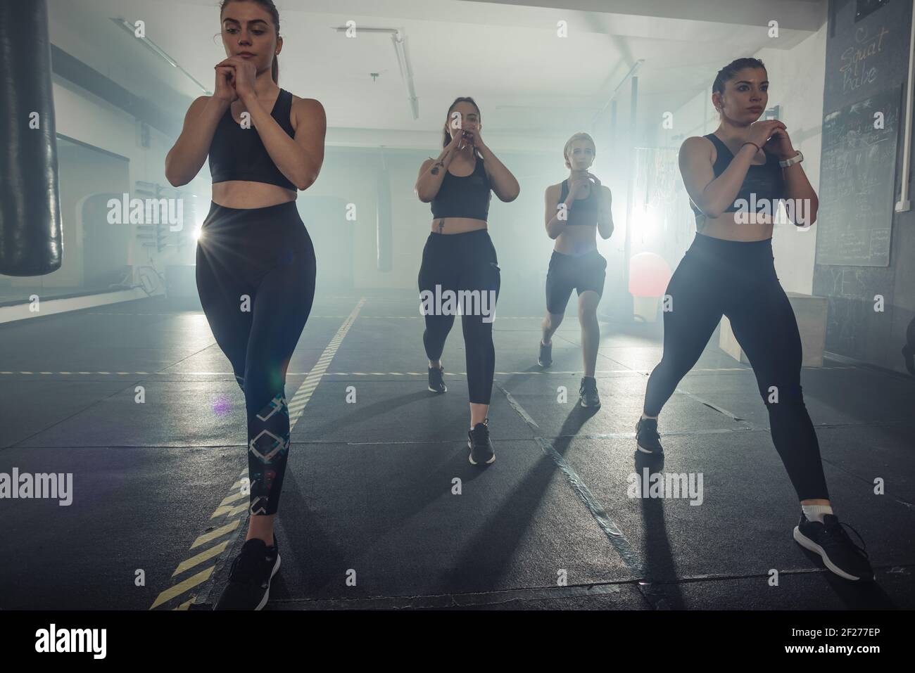 Group of sportswomen in sportswear doing lunge exercise at the gym with ...