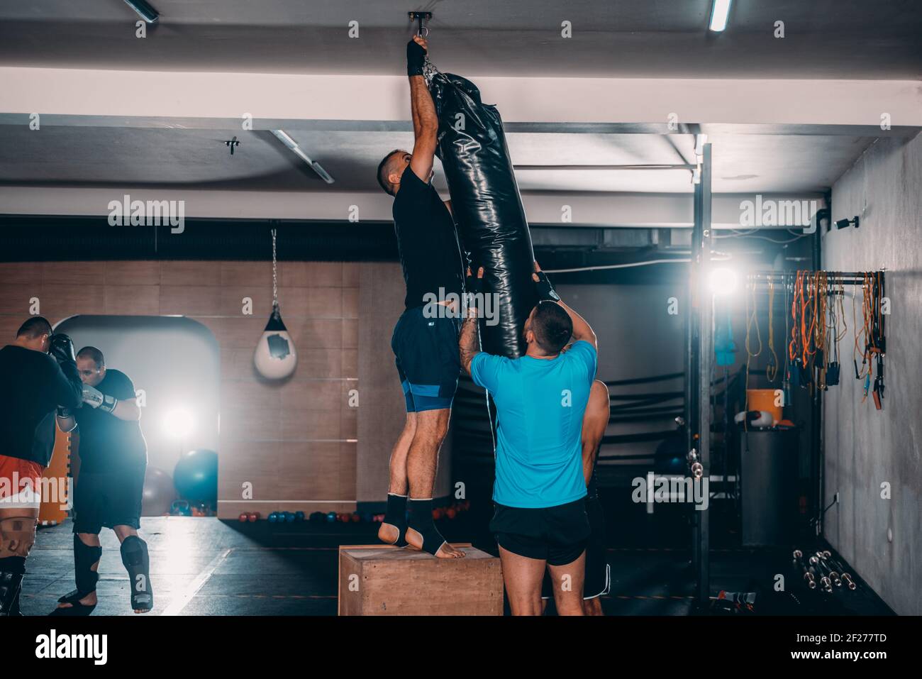 Sporty man set up boxing bag on the wall in underground garage Stock ...