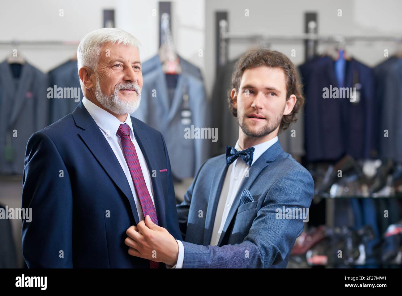 Two elegant men picking up fashionable suits in store. Concept of ...