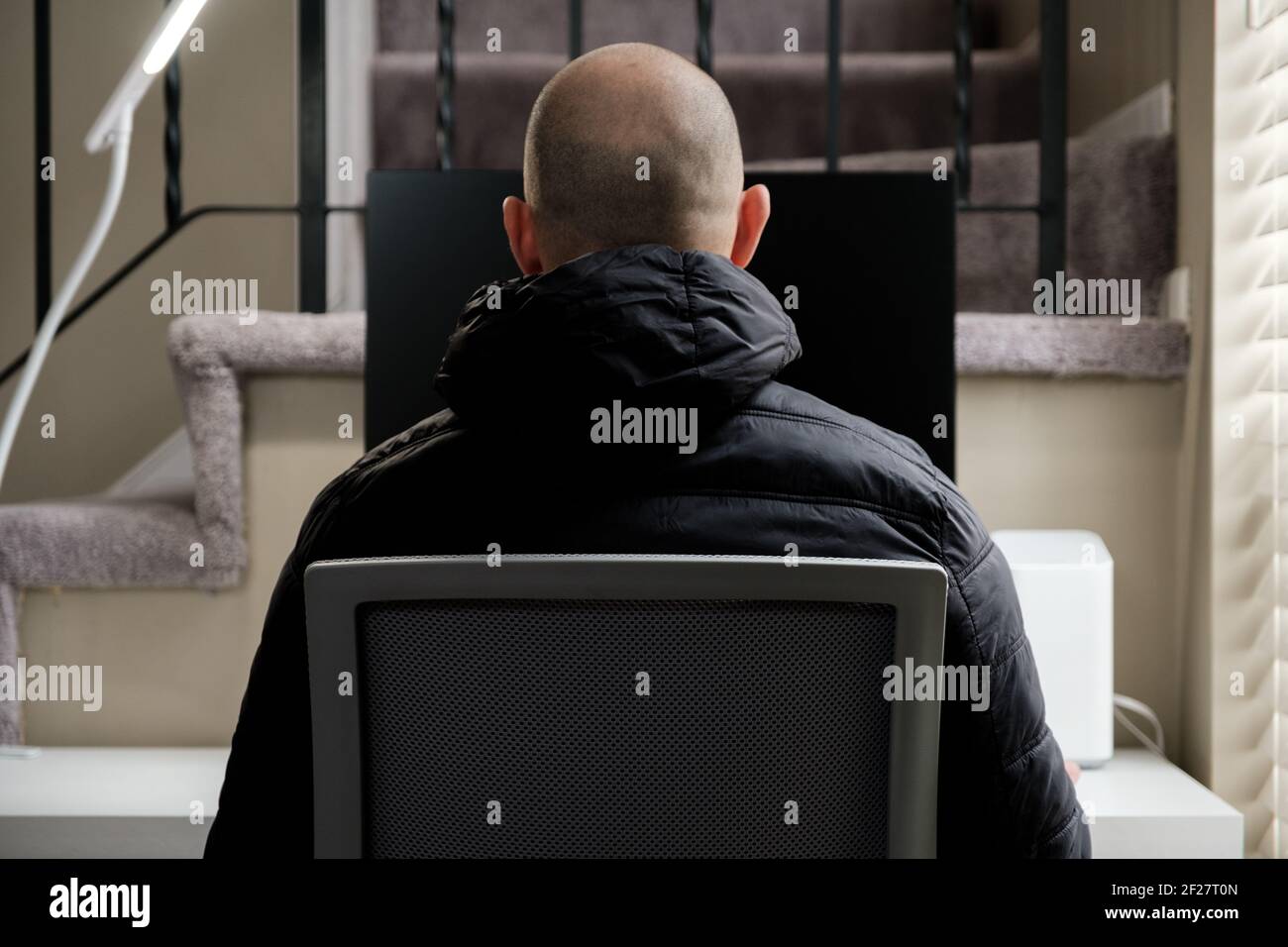 A man sitting on a chair in front of a computer from behind Stock Photo ...