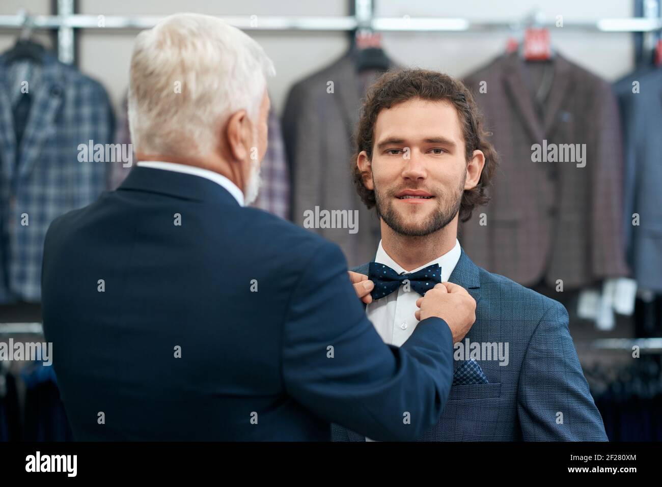 Close up of senior man helping son choose bow tie in store. Concept of ...