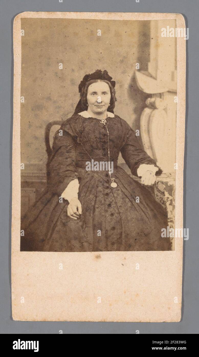 Portrait of a woman. Sitting woman next to a table. On the right a part ...