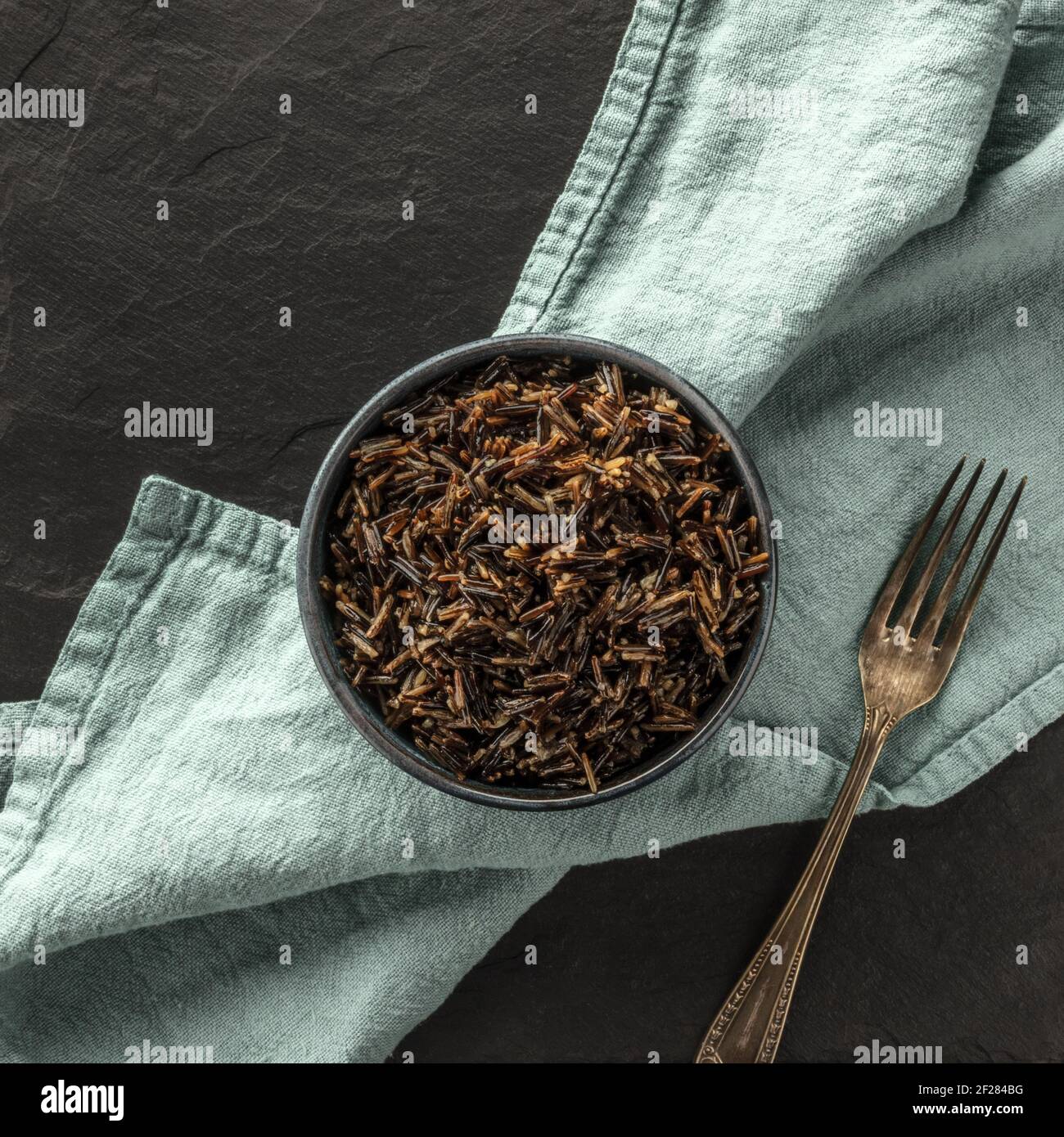 A square photo of wild black rice, shot from the top on a black ...