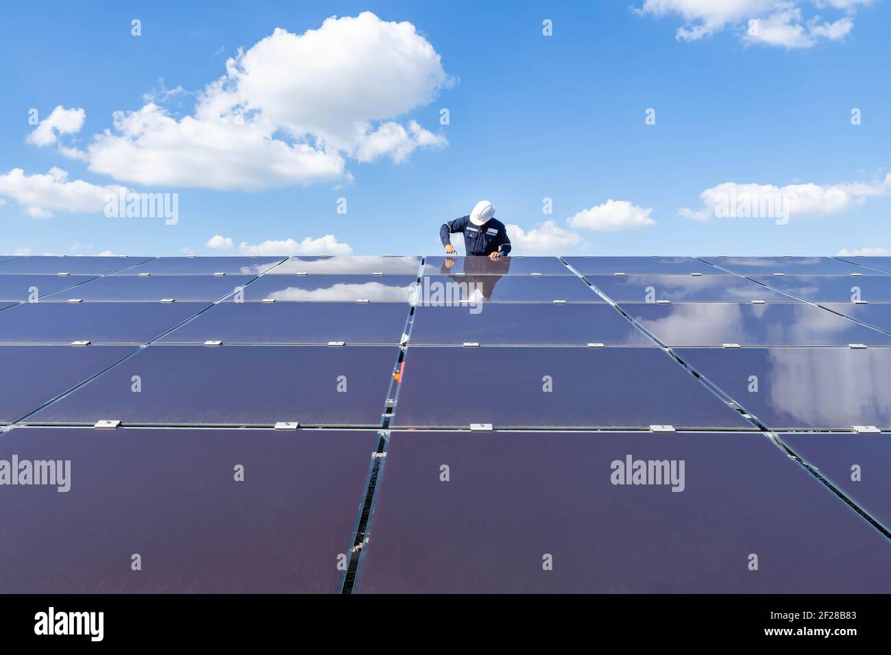 The solar farm with the technician is removing the nut to replace the ...