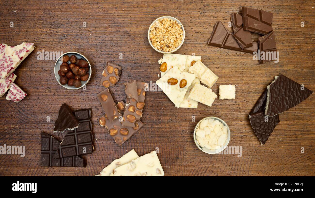 many different types of chocolate lie on a brown background with nuts ...