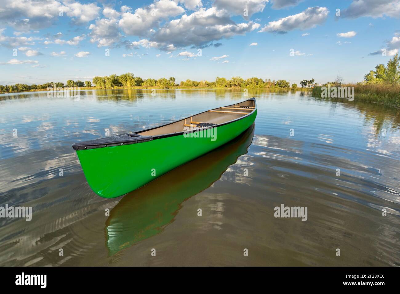 green canoe on a calm lake in a fisheye perspective, late summer in ...