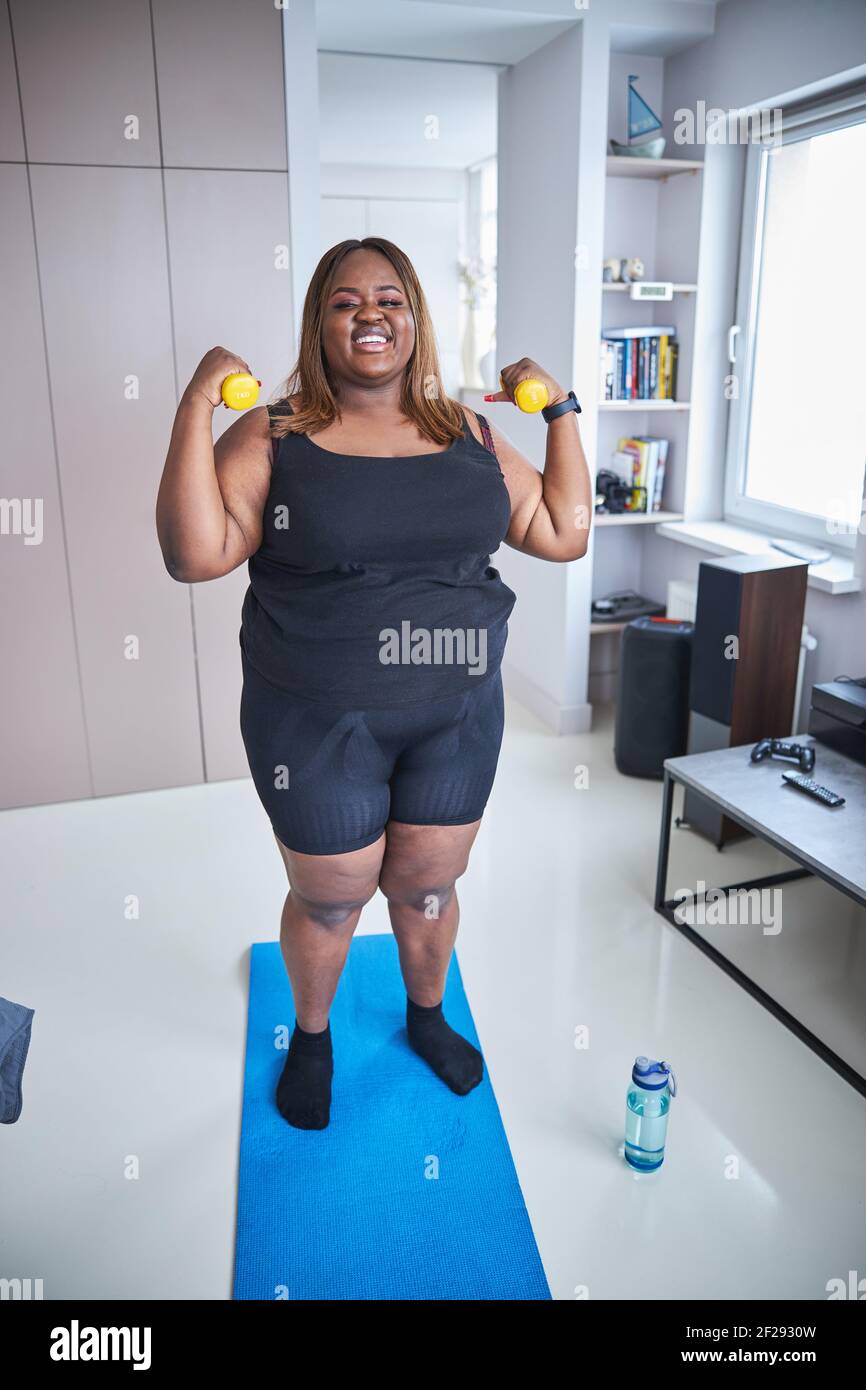Inspired plus-size lady is exercising with dumbbells Stock Photo - Alamy