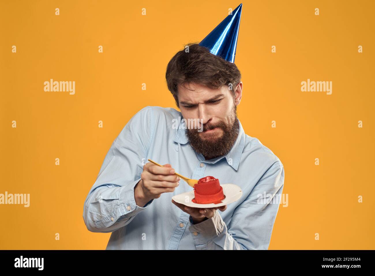 a man with a birthday cake in his hands and in a cap on a yellow ...