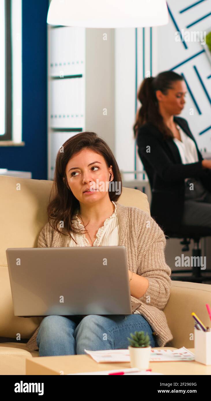 Manager woman sitting on couch holding laptop and talking on video call ...