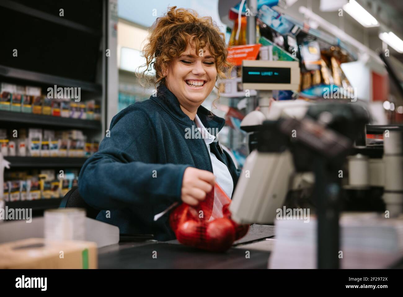 Female cashier passing the products through the bar code reader at ...
