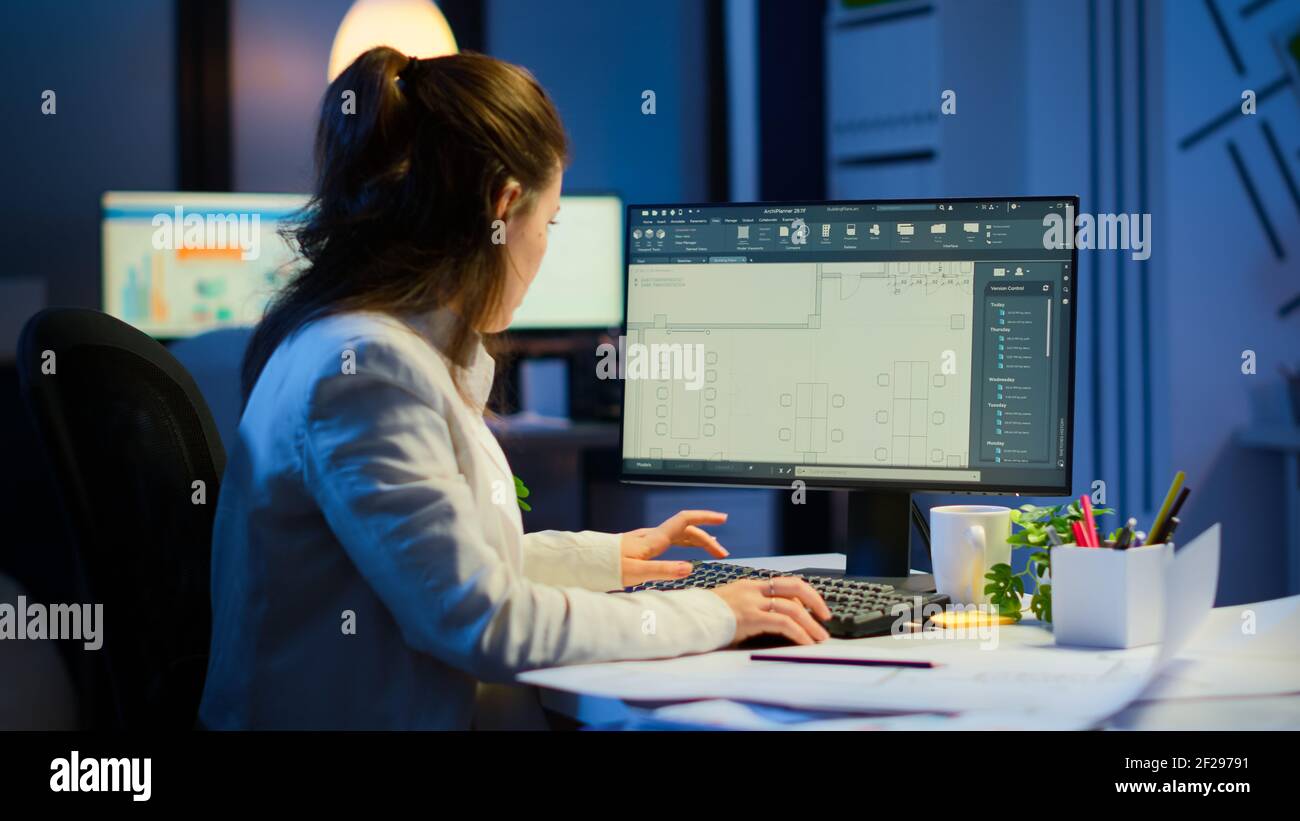 Woman architect matching digital plans from pc with blueprints working ...