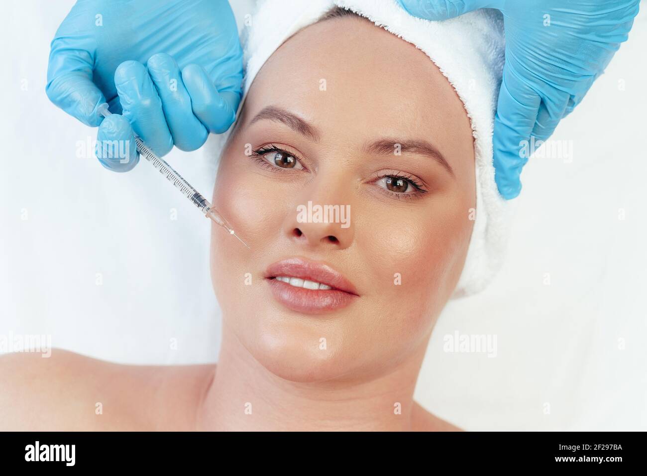 Portrait of a beautiful woman having an injection of botox in her face ...