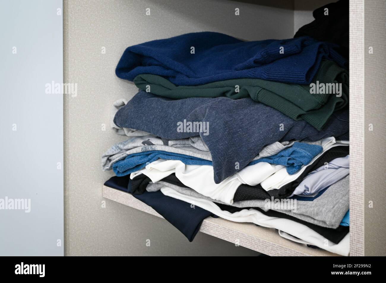 Clothes messy piled up on the closet shelf Stock Photo - Alamy