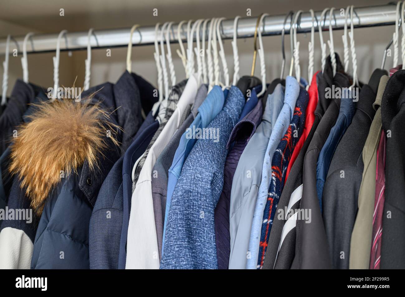 Various clothes hanging on hangers and filling the closet Stock Photo ...