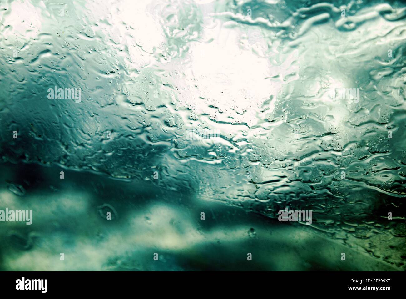 Road view through car window with rain drops. Driving in rain ...