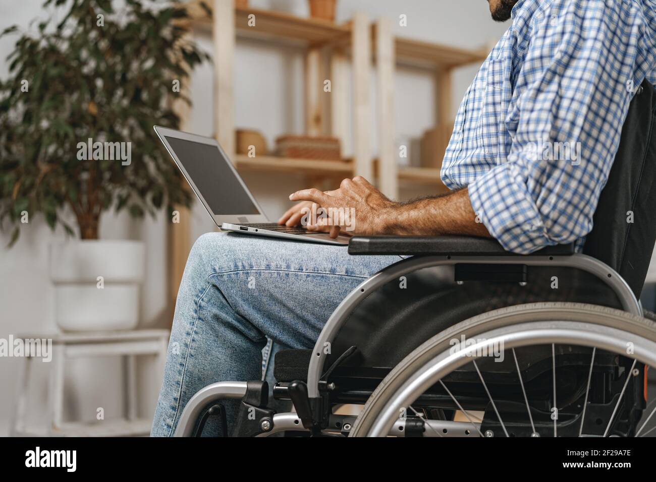 Disabled man sitting in a wheelchair and using laptop Stock Photo - Alamy