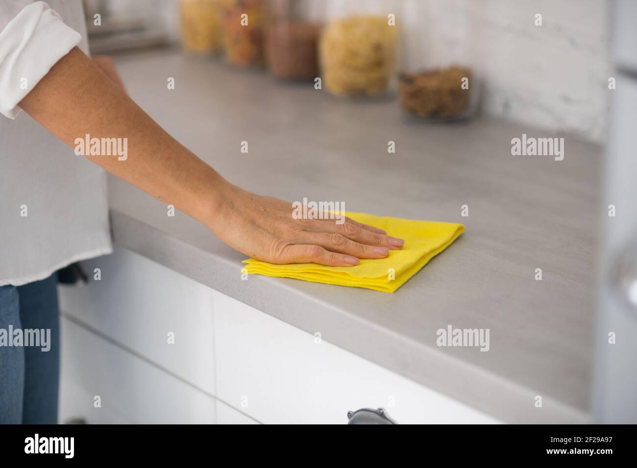 Woman wiping the table surface with a yellow household cloth Stock ...