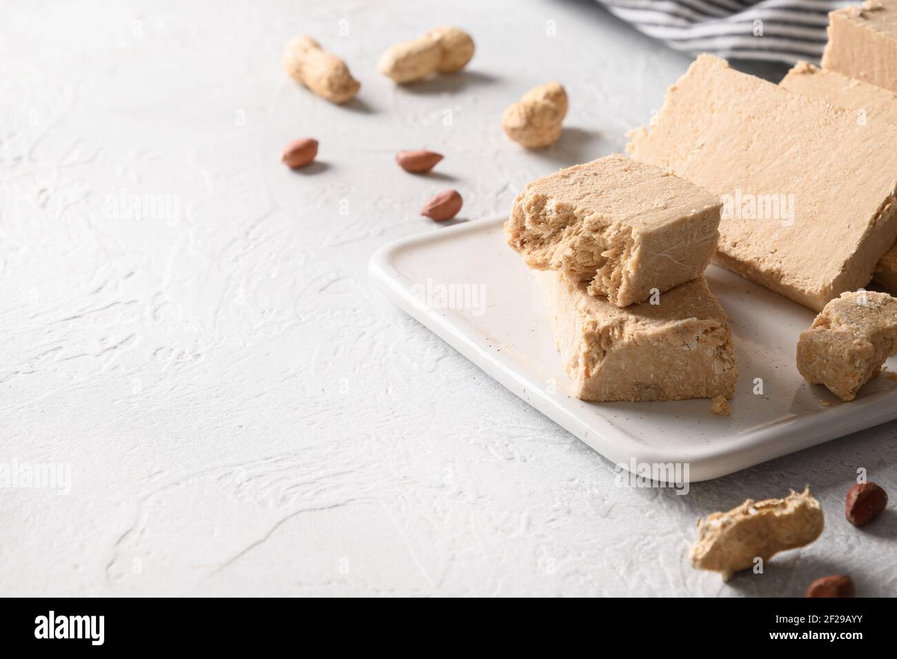 Tasty sweet dessert halva prepared from peanut on a white background ...