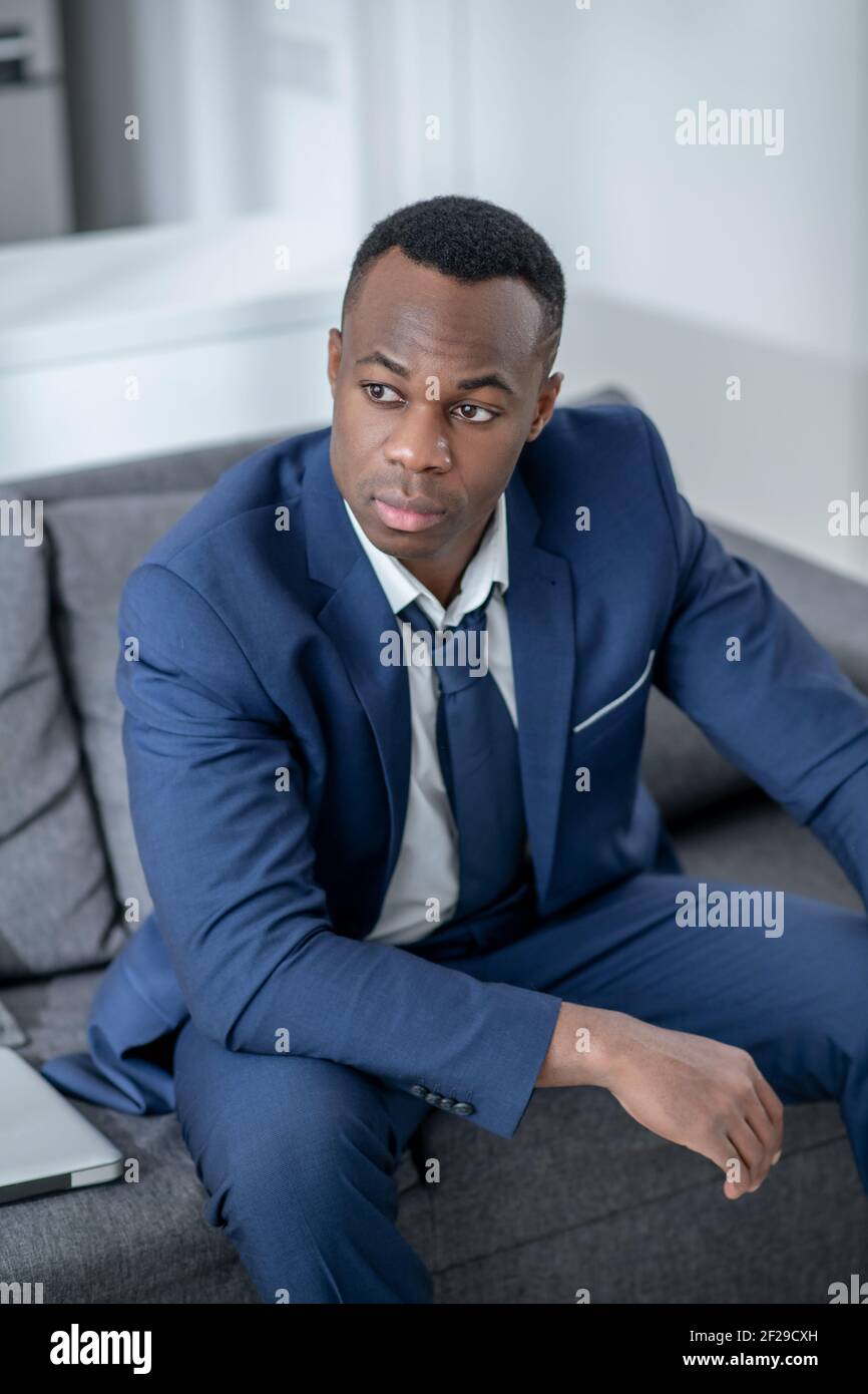 Elegant dark-skinned man sitting and looking anticipated Stock Photo ...