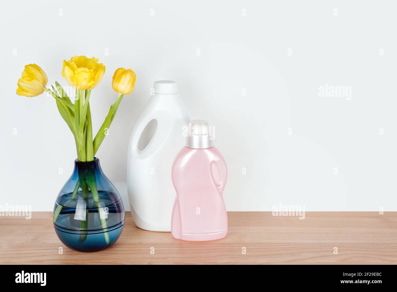 Bottles of detergent and fabric softener with yellow tulip flowers on ...