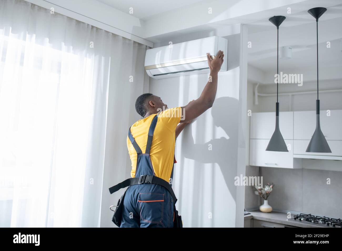 Service man in yellow tshirt looking busy while installing the air ...
