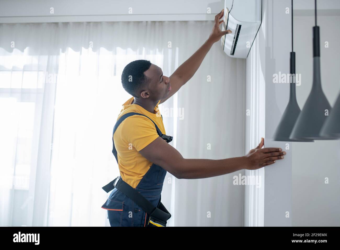 Service man in yellow tshirt looking busy while installing the air ...