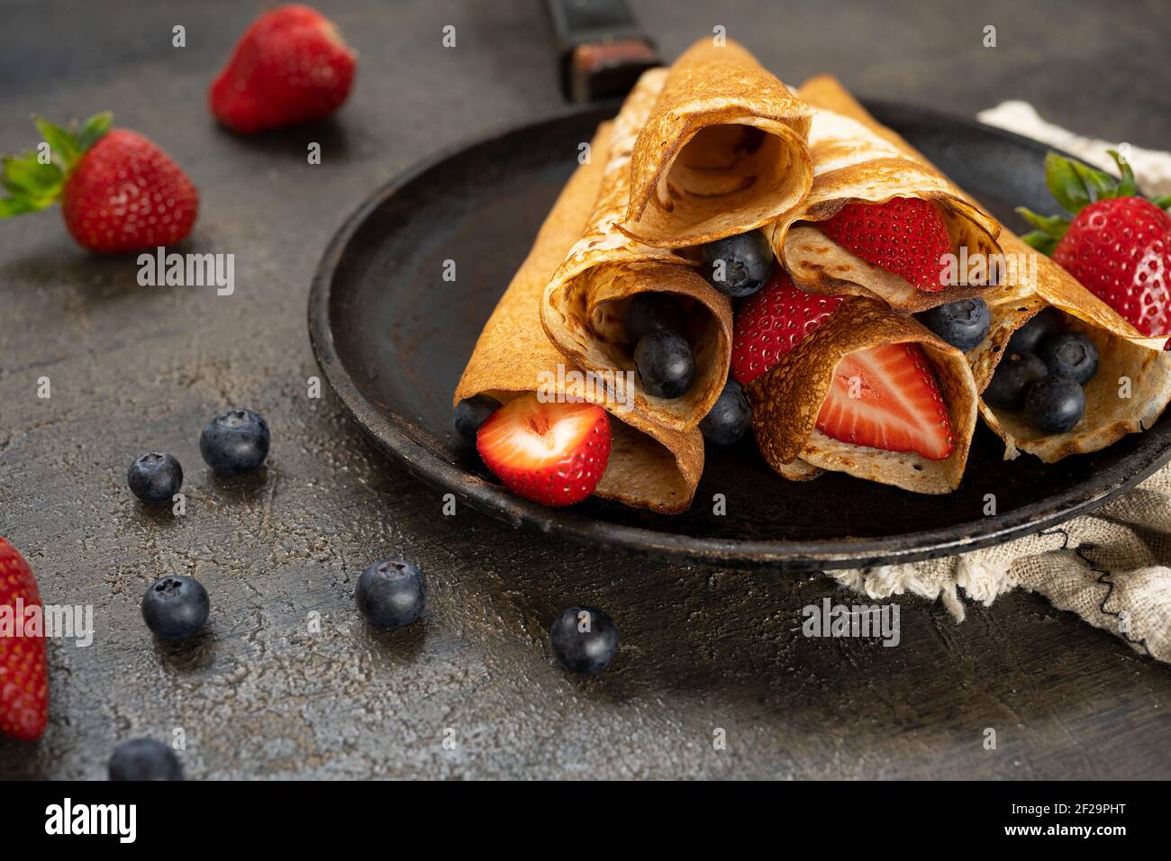Tasty homemade rustic pancake with berries in a frying pan on wooden ...