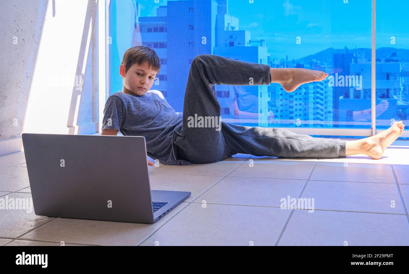 Child watching online video on laptop computer and doing sport fitness ...