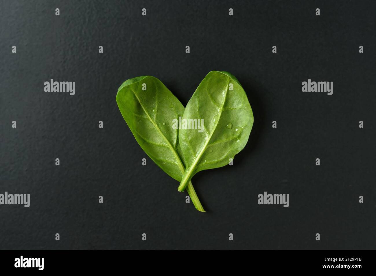 Spinach leaves in heart shape on black background Stock Photo - Alamy