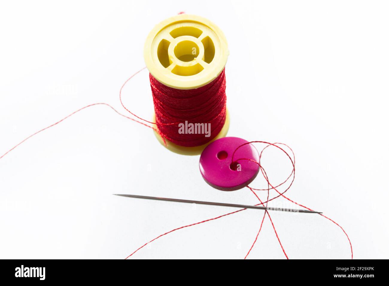 Button with two holes. Thin red thread Stock Photo - Alamy