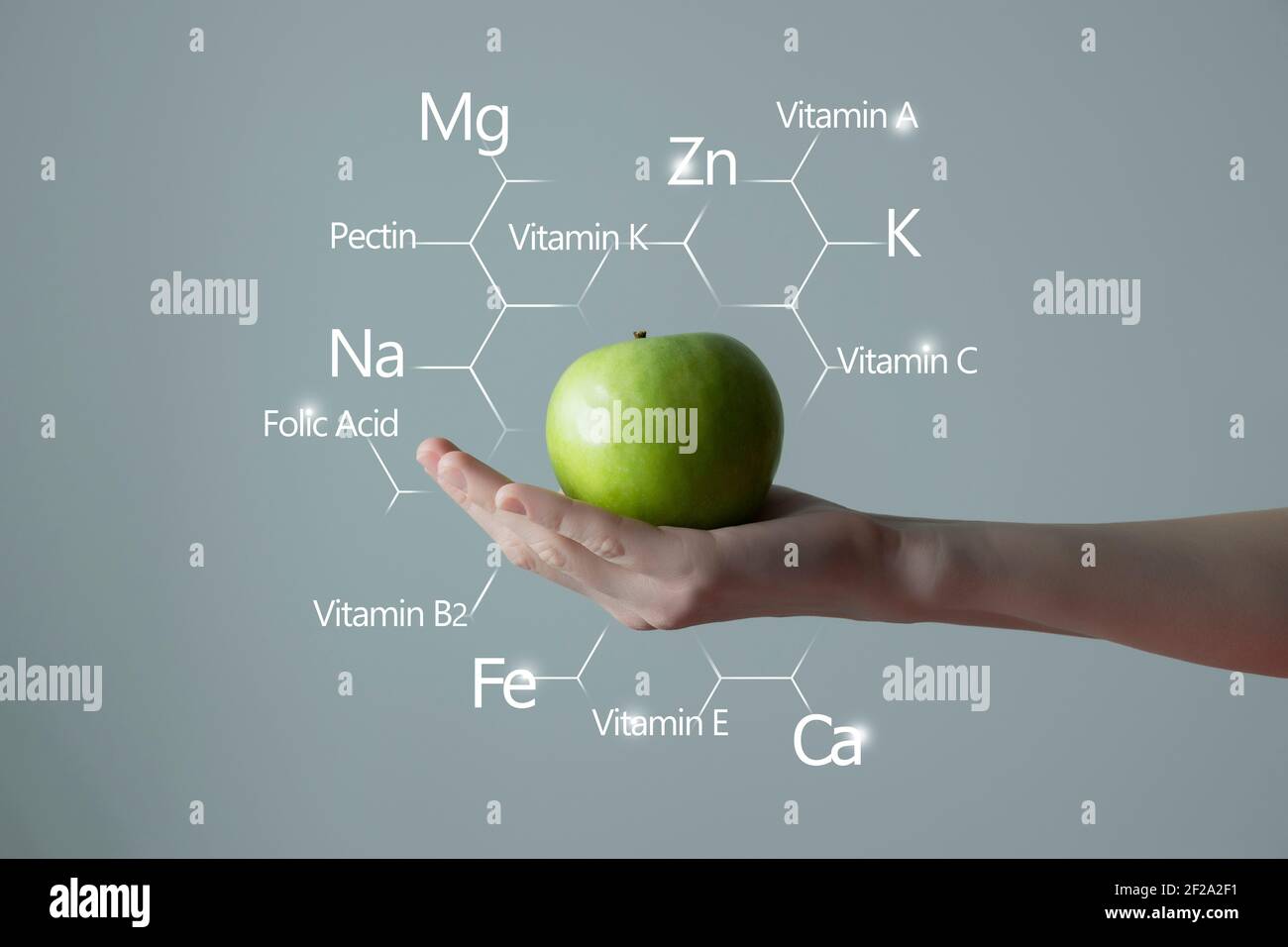 Woman`s hand holding green apple, molecular structure with vitamins and ...