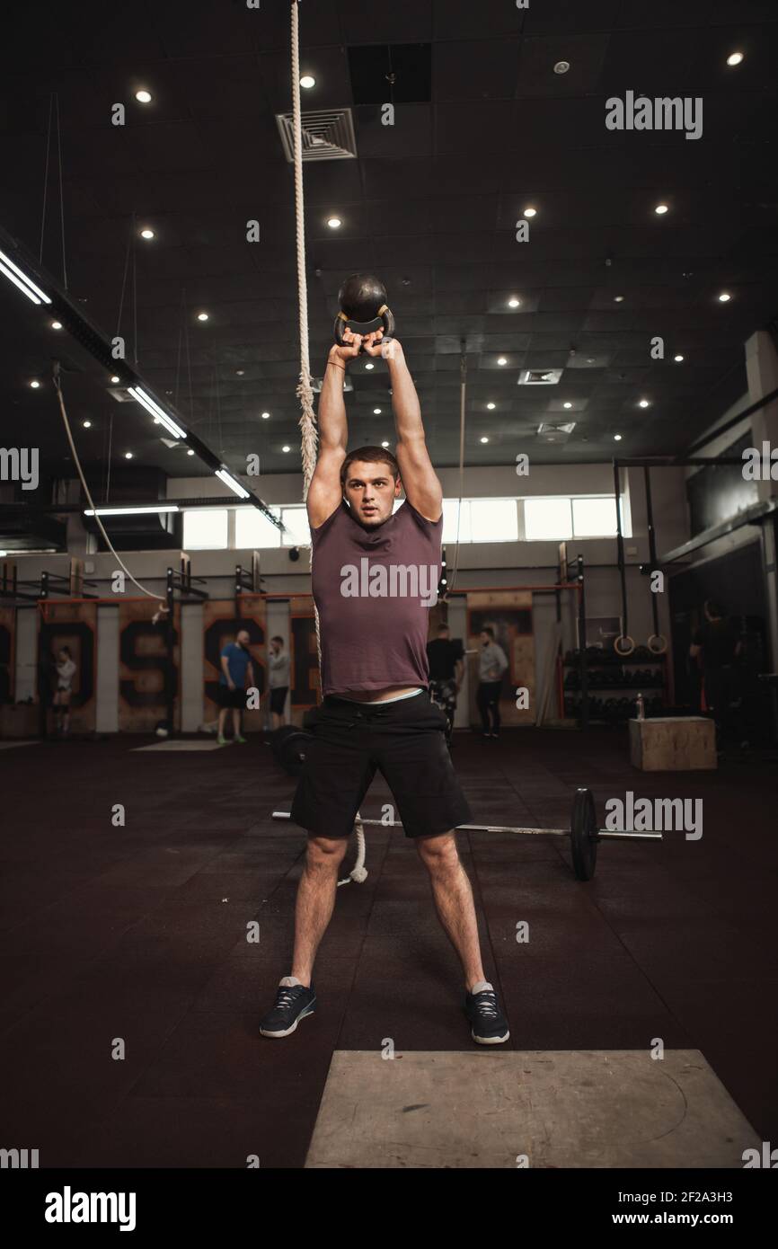Vertical shot of a handsome sportsman doing kettlebell swing exercise ...
