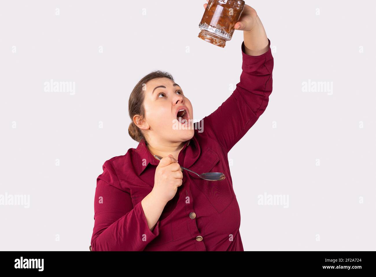 Portrait of a chubby woman with a spoon and a large jar of chocolate ...