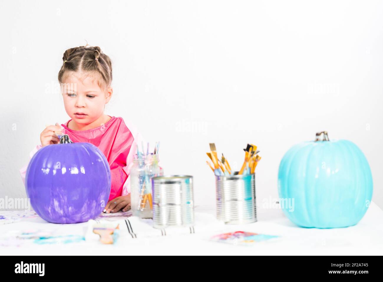 Little girl painting small craft pumpkin with purple acrylic paint ...