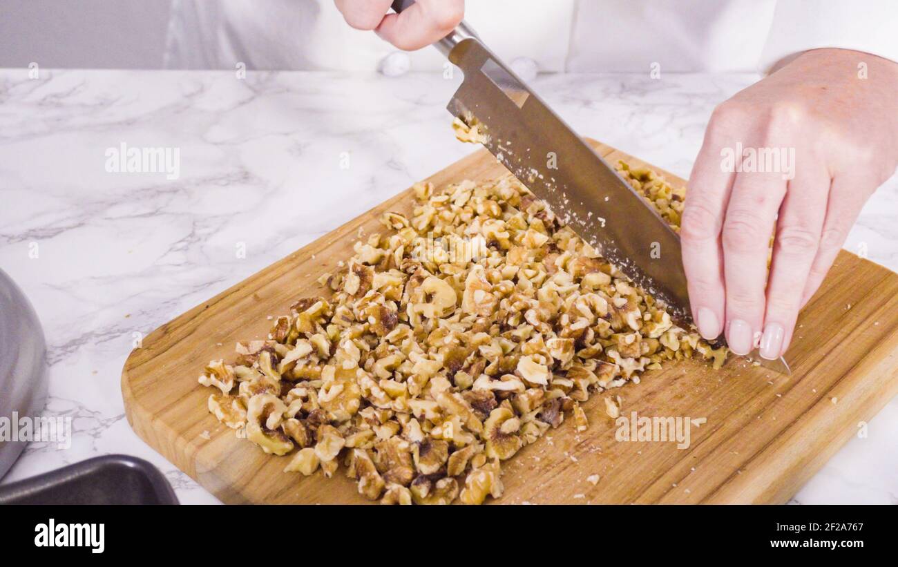 Step by step. Chopping walnuts with kitchen knife on a wood cutting ...