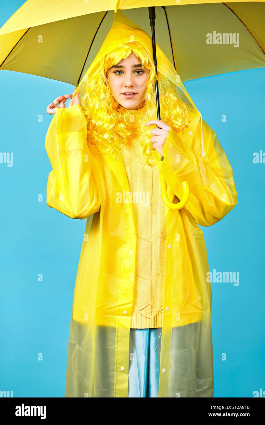 pretty teen girl in a yellow raincoat with an umbrella and a hood on ...