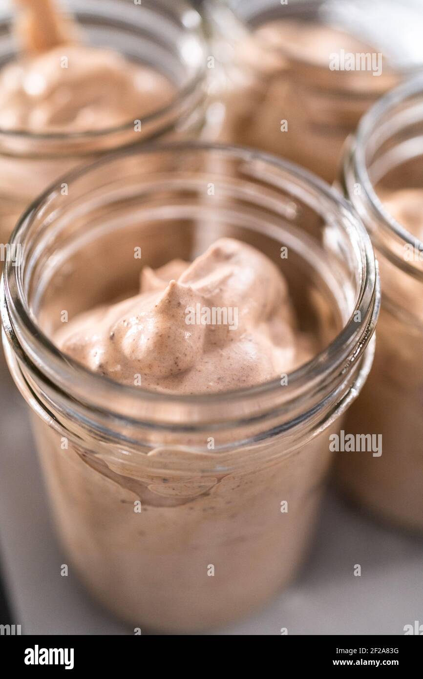 Scooping mixture into the small glass jars to make homemade chocolate ...