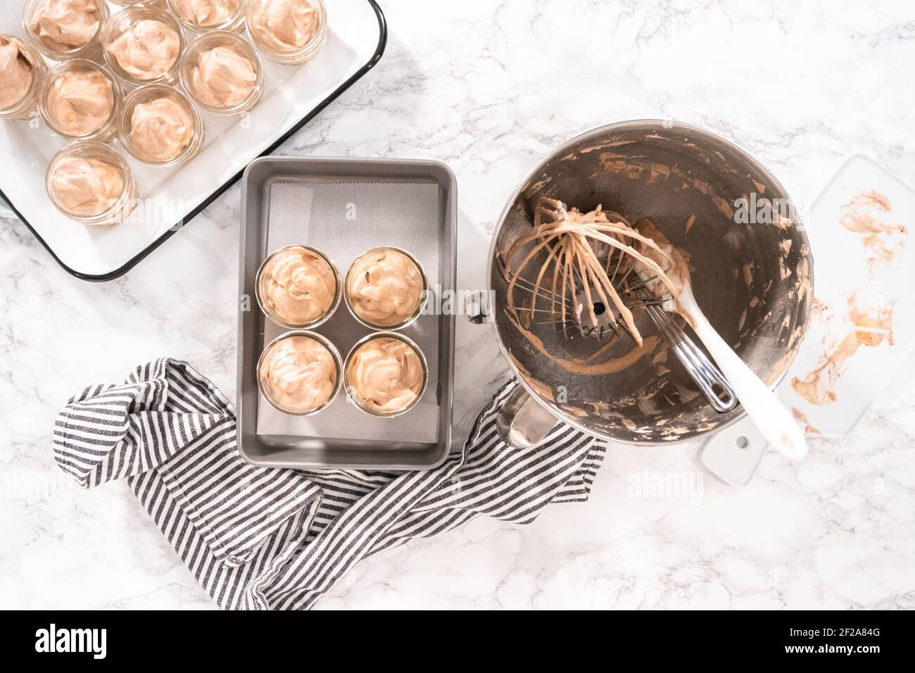 Flat lay. Scooping mixture into the small glass jars to make homemade ...