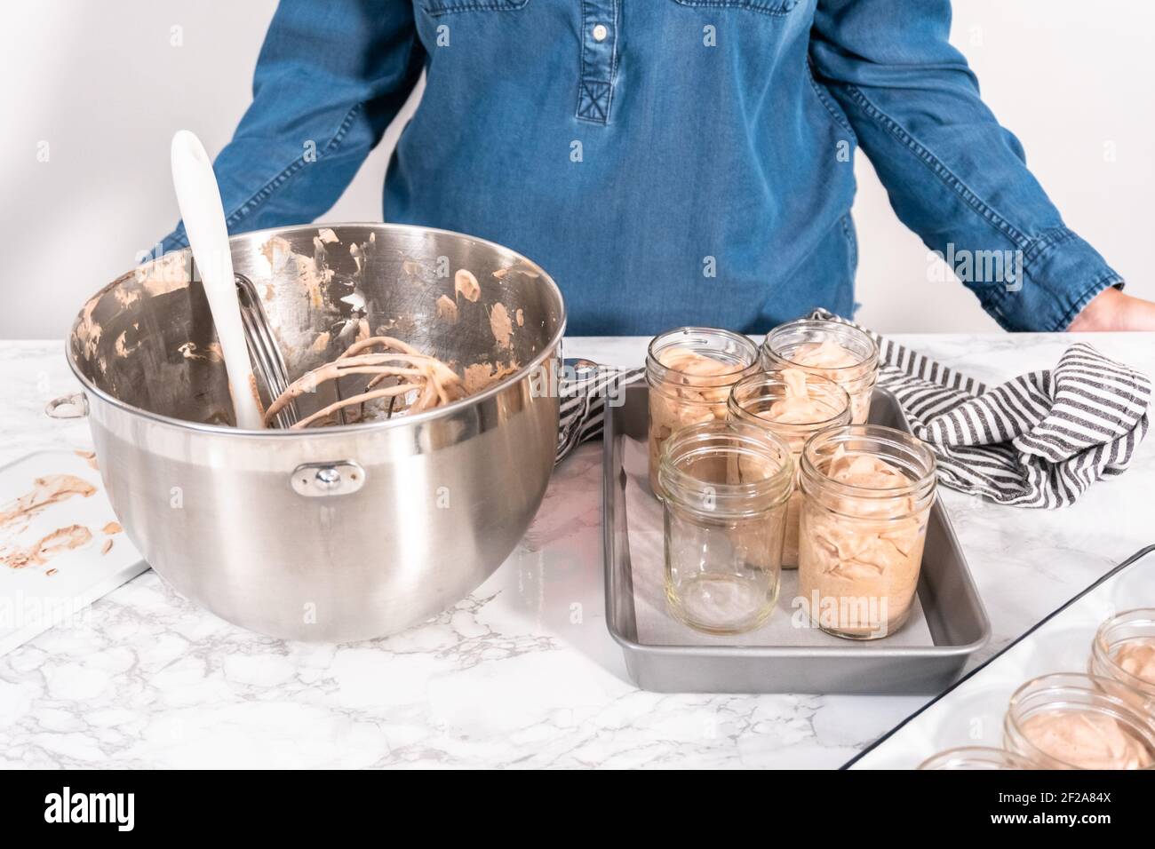 Scooping mixture into the small glass jars to make homemade chocolate ...