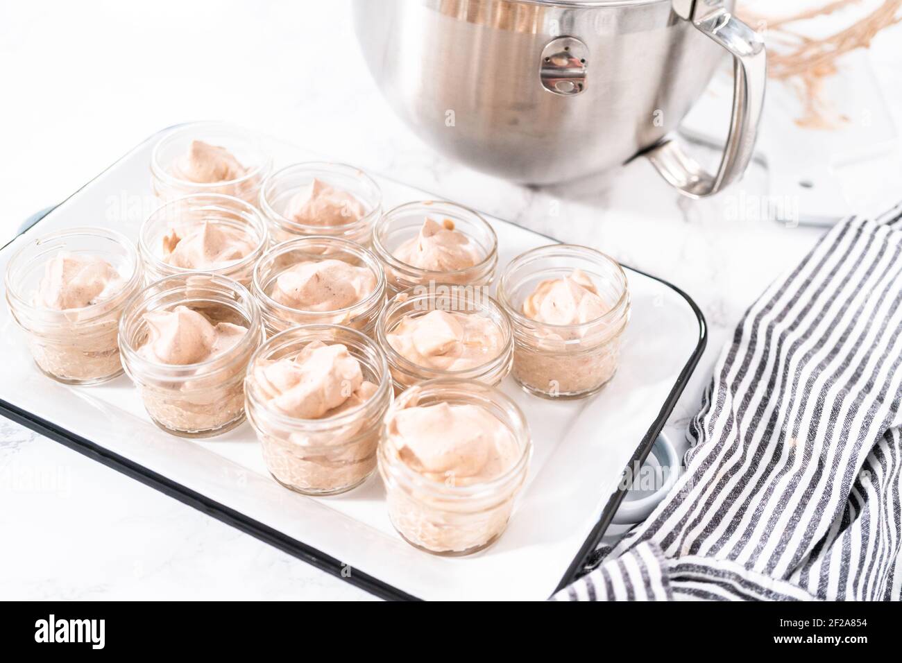 Scooping mixture into the small glass jars to make homemade chocolate ...