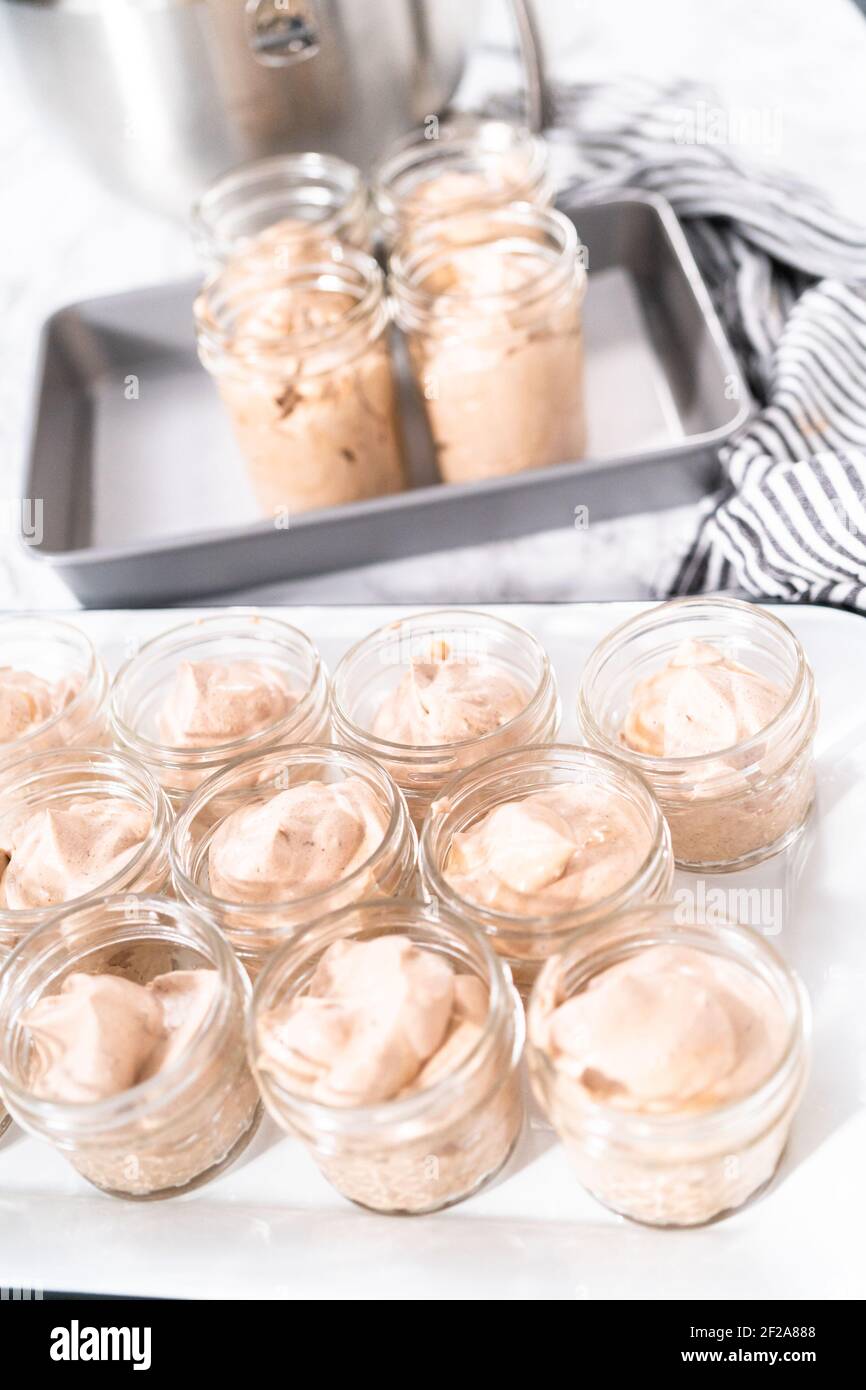 Scooping mixture into the small glass jars to make homemade chocolate ...