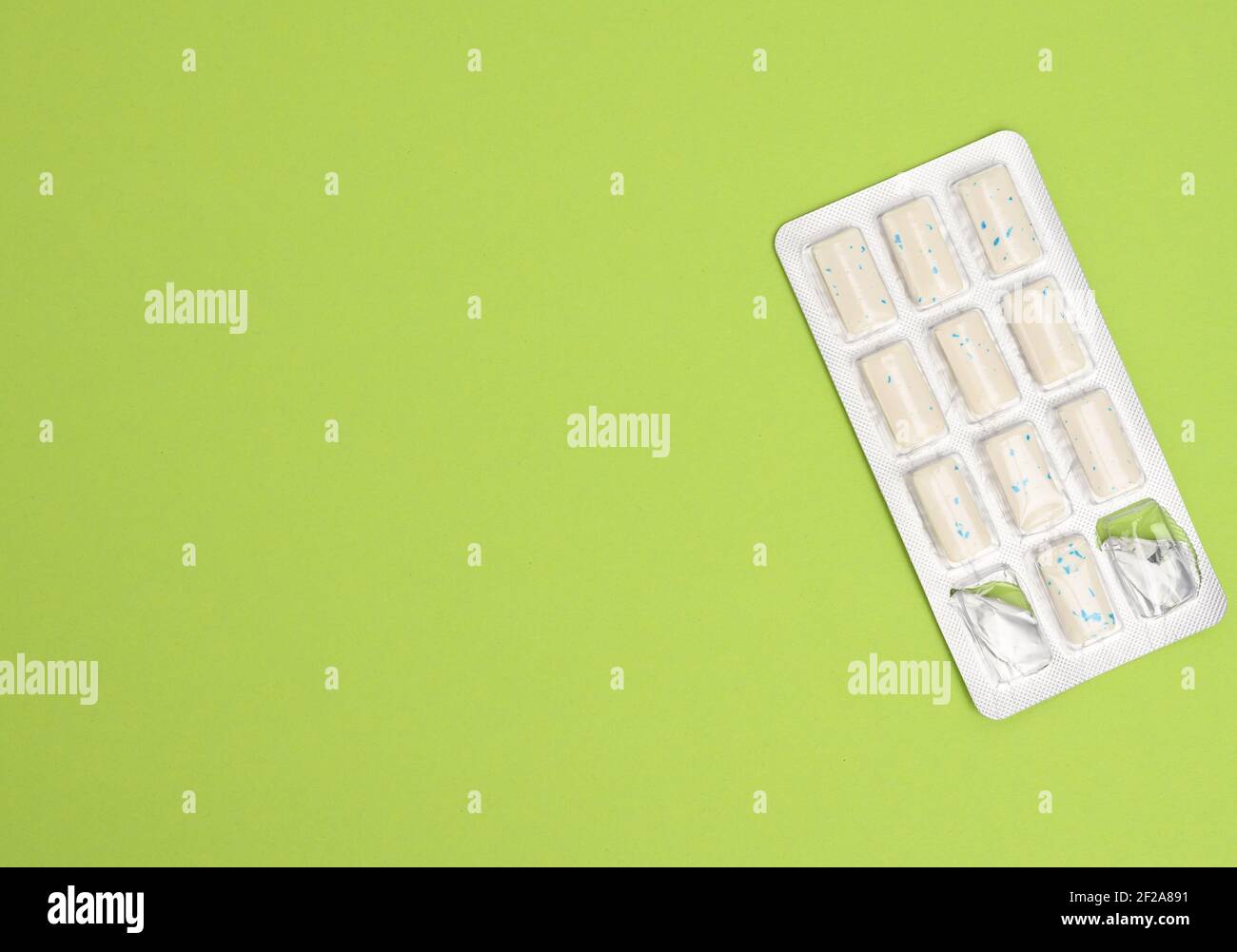 rectangular pieces of gum in a blister pack on a green background, copy ...