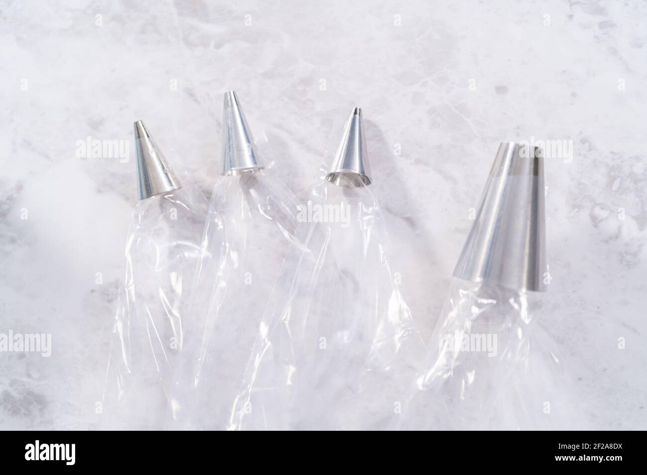Empty piping bags with metal piping tips on the counter Stock Photo - Alamy