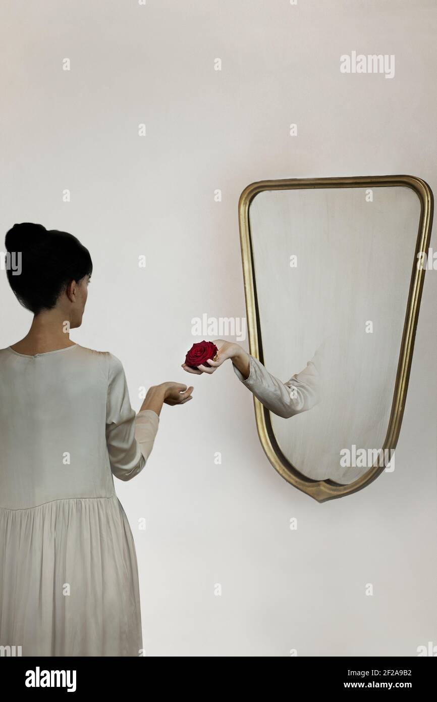 surreal gesture of a hand coming out of the mirror to give a rose to a ...
