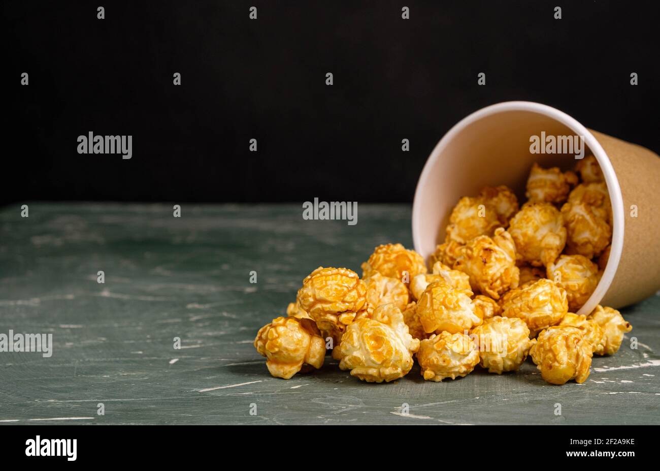 Popcorn in paper cup on green background Stock Photo - Alamy