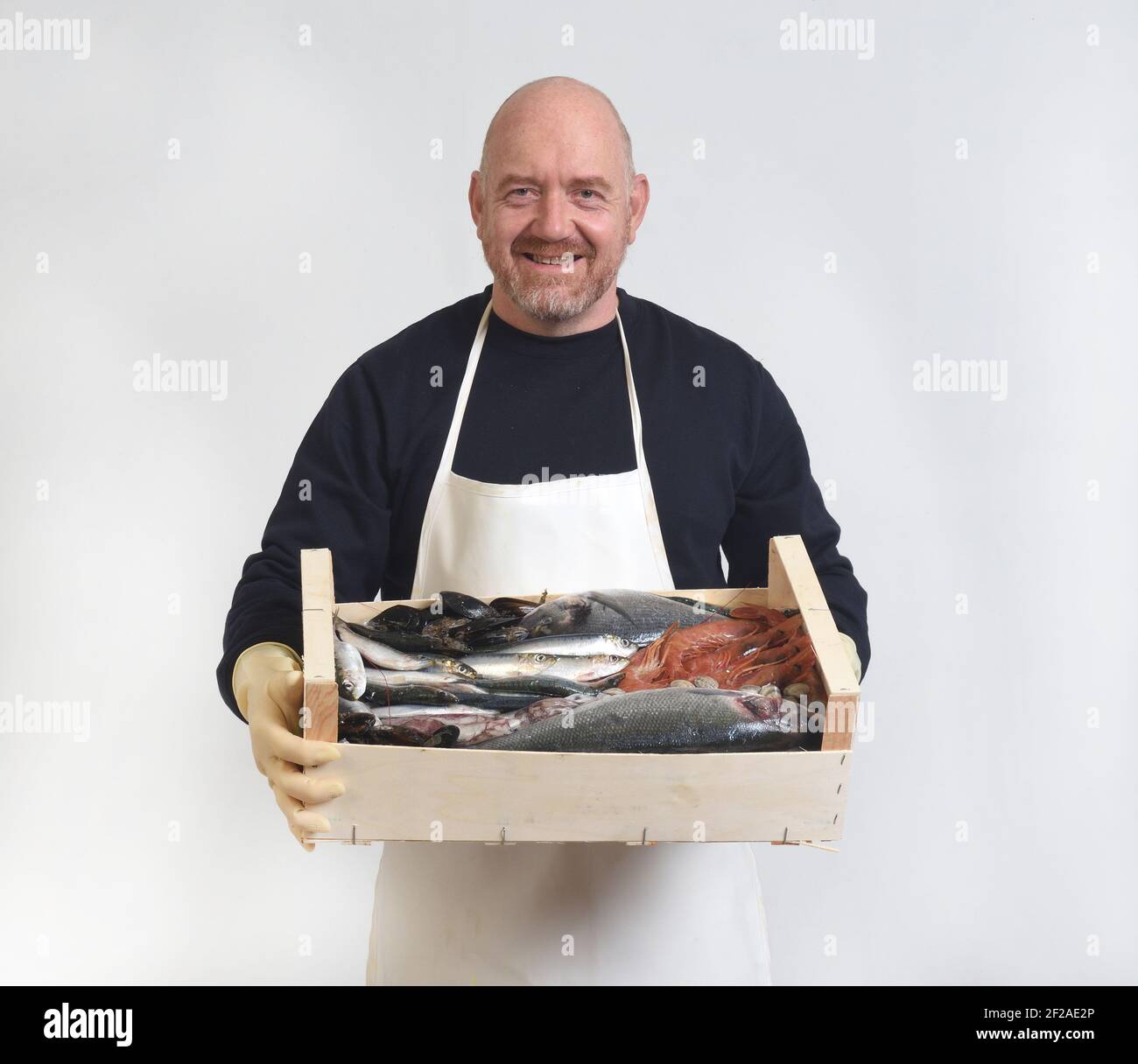 portrait of a fishmonger with a box with seafood on white background ...