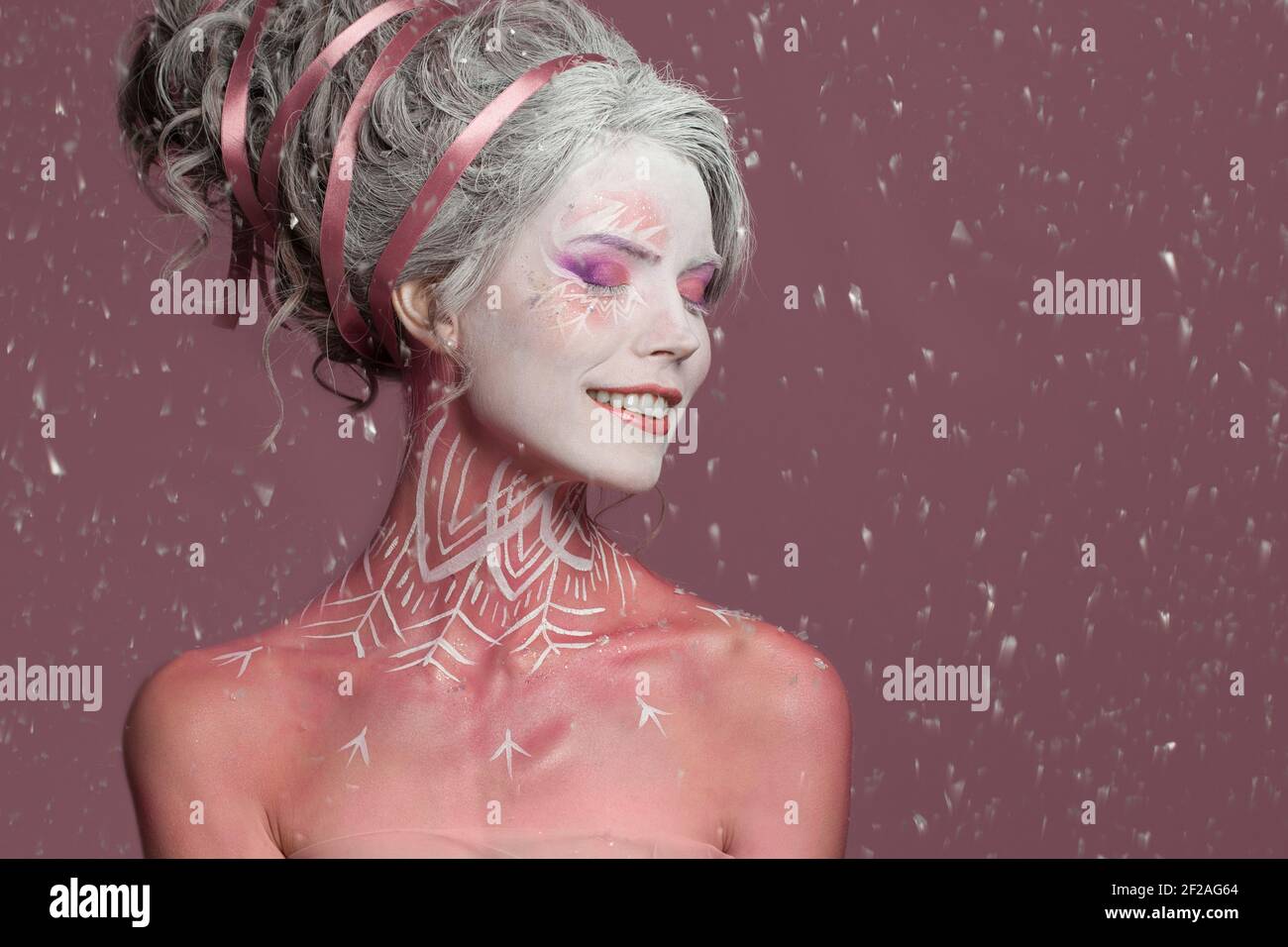 Happy winter woman with snowflake on her face in snow on pink ...