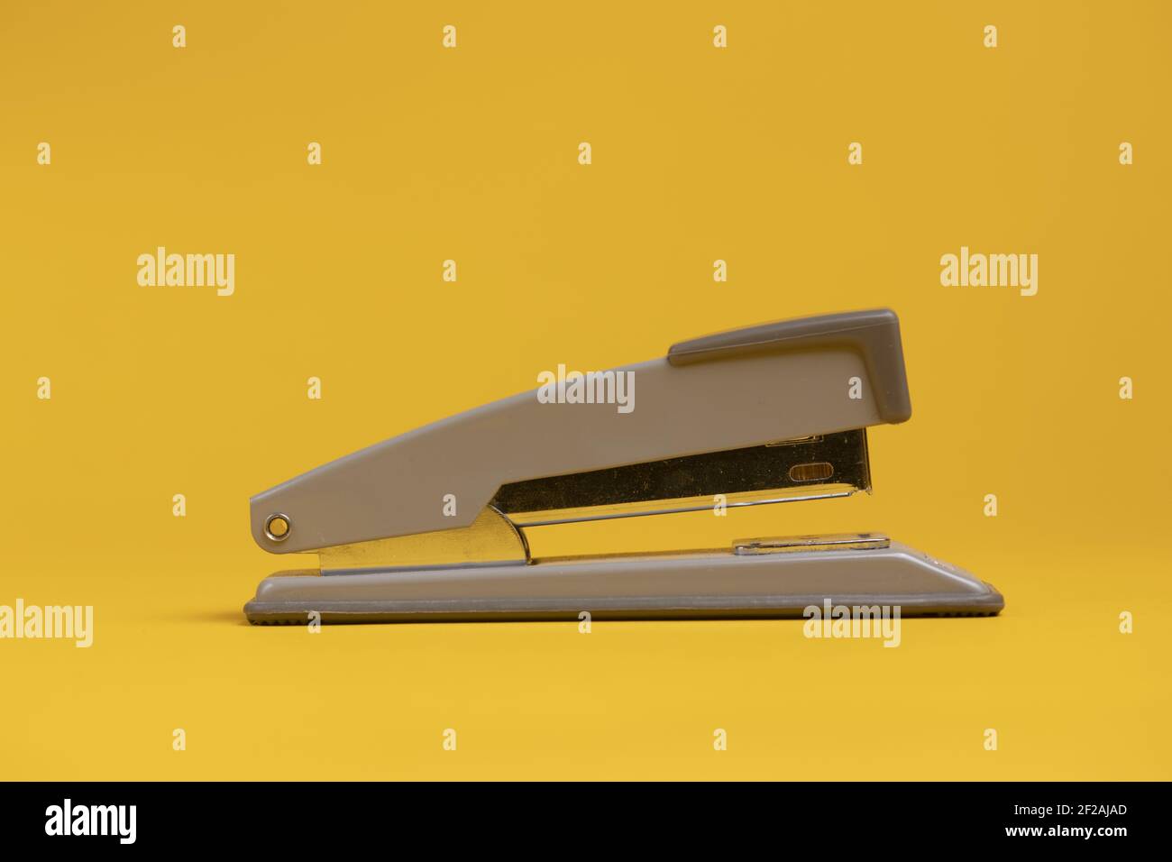 Stapler office tool still life against a seamless solid yellow ...
